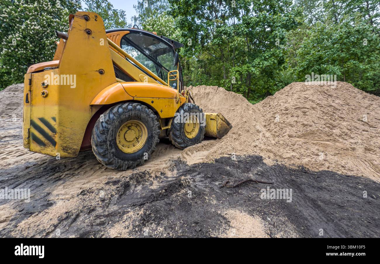 construction machine for earthworks. skid steer loader is leveling ...