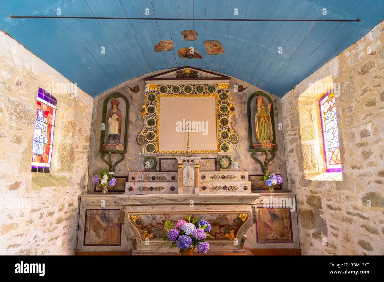 Marble altar, statues, cross and stained glass windows inside a small ...