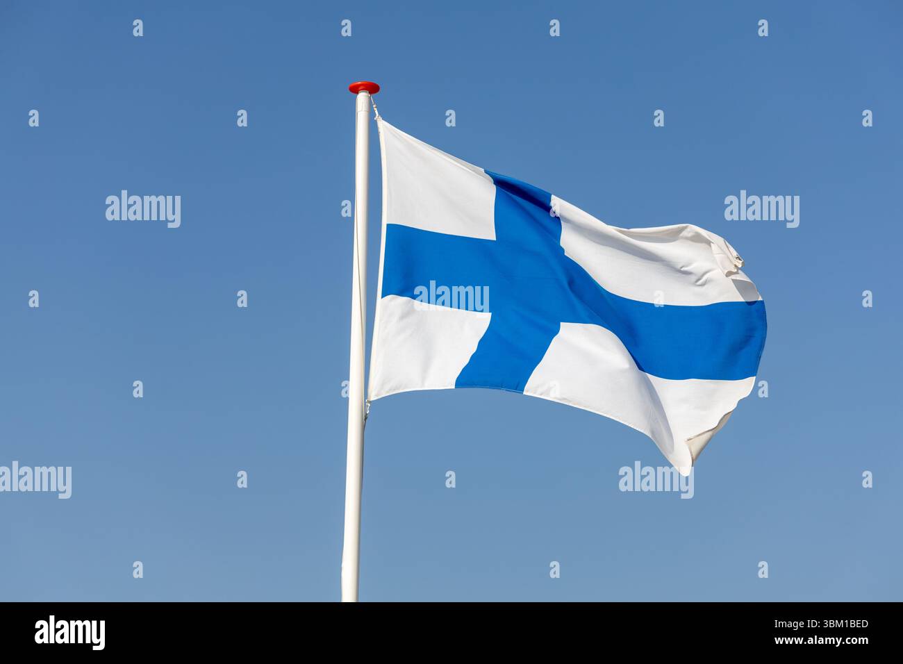 Finnish flag waving in the wind against a clear blue sky. A symbol of ...