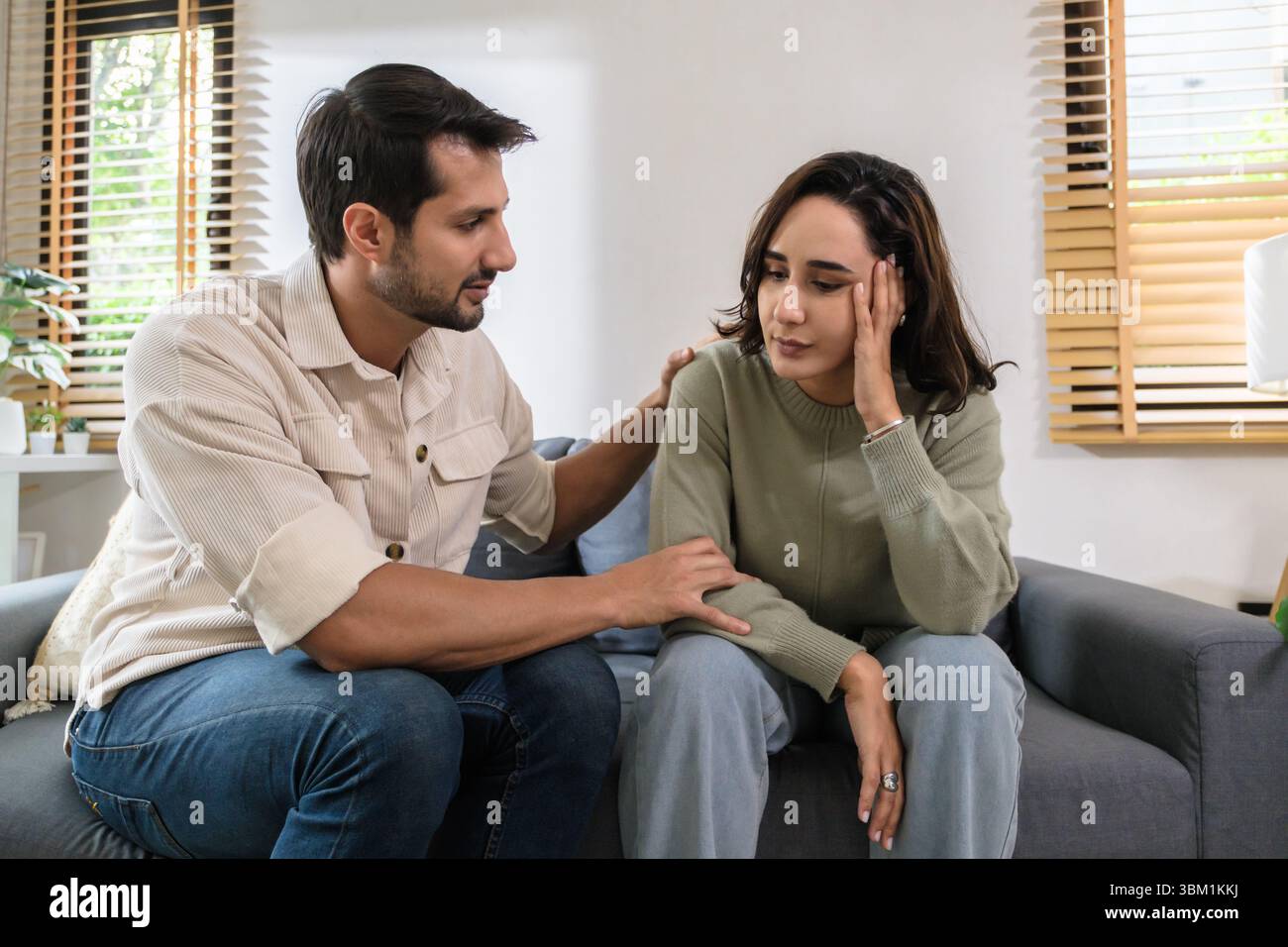 Supportive couple in emotional moment at home as woman struggles with ...