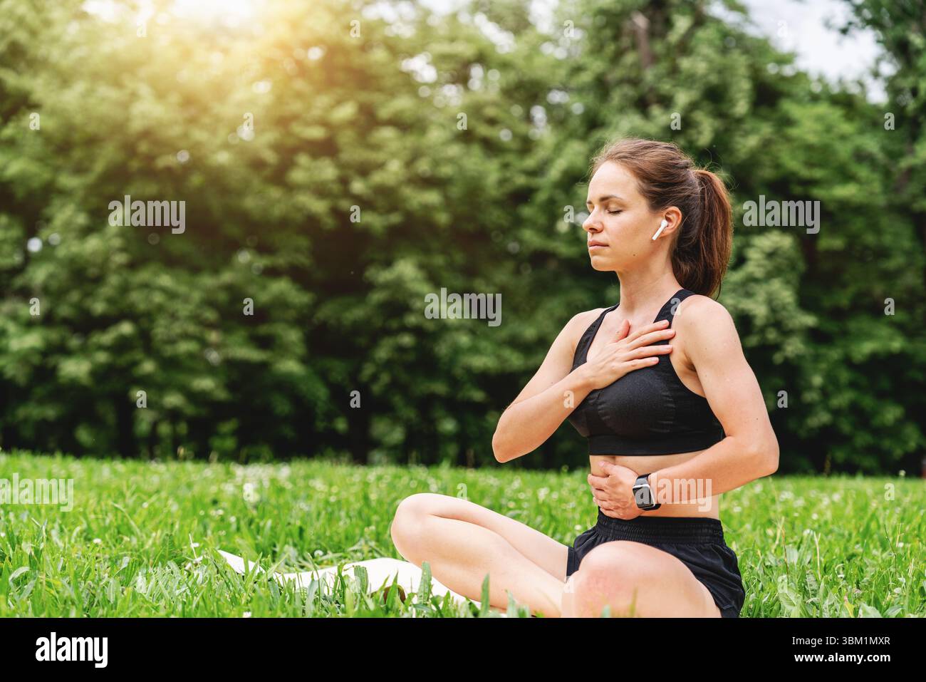 Serene woman in lotus pose doing breathing exercise outdoors in park ...