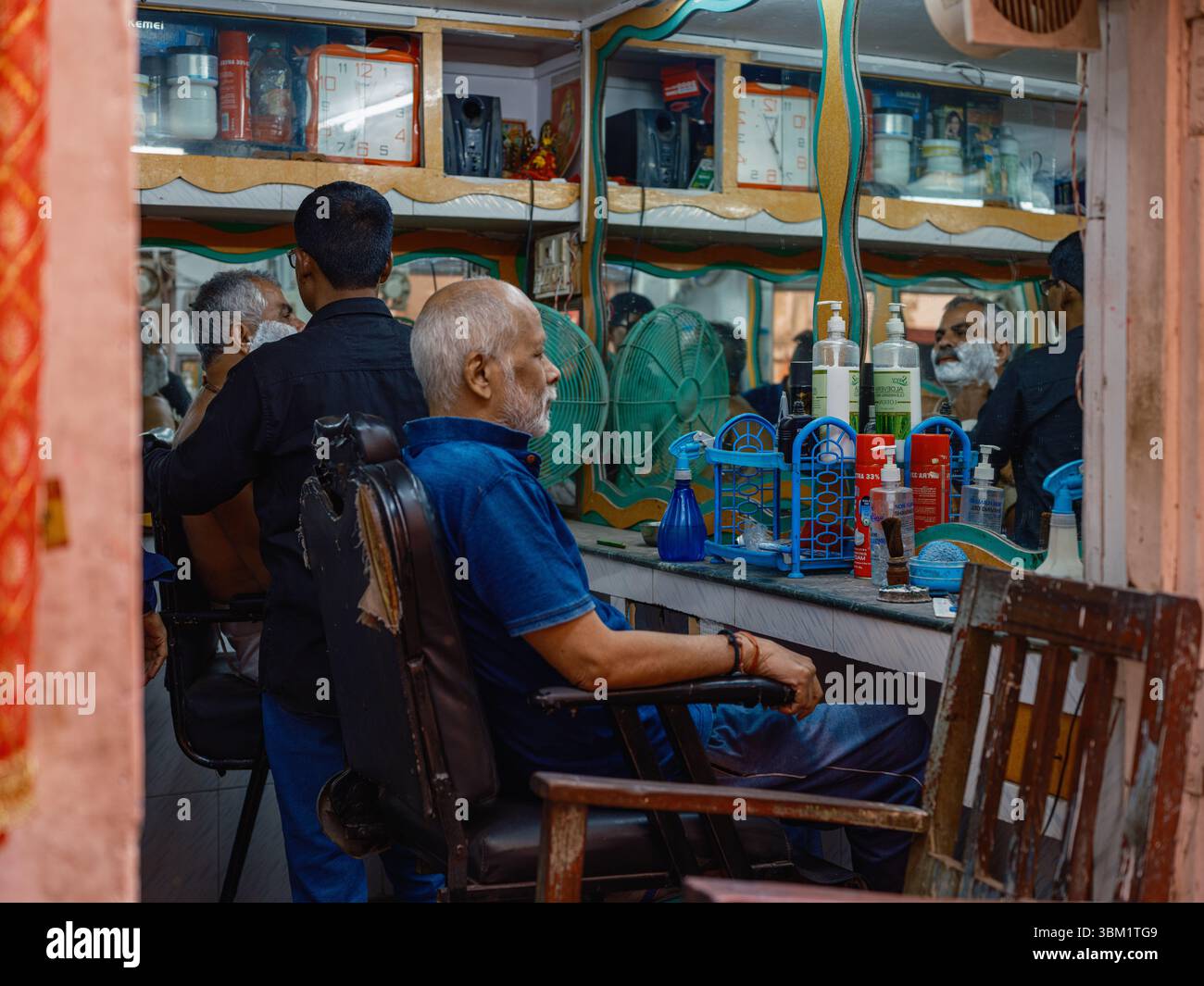 India, Varanasi, 16 Mar 2025. Customer sits in a vintage barber’s chair ...