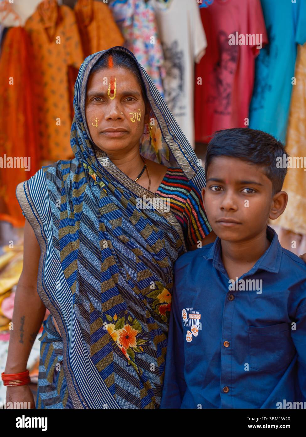 India, Varanasi, 16 Mar 2025. Woman with decorative tilak and her son ...