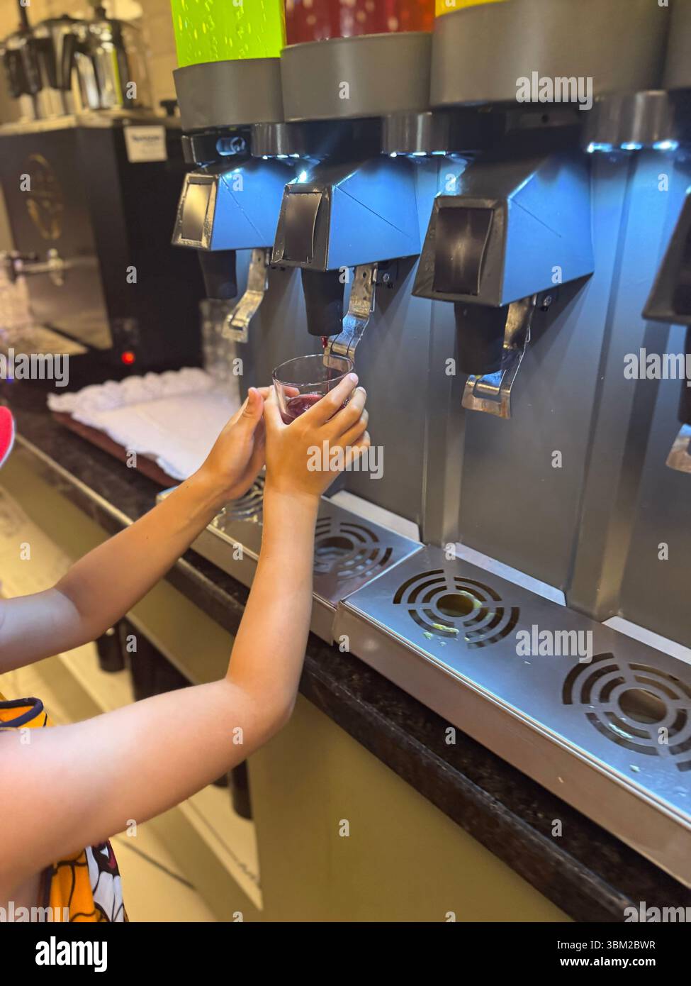Child pouring a drink from a self-service beverage machine at an all ...