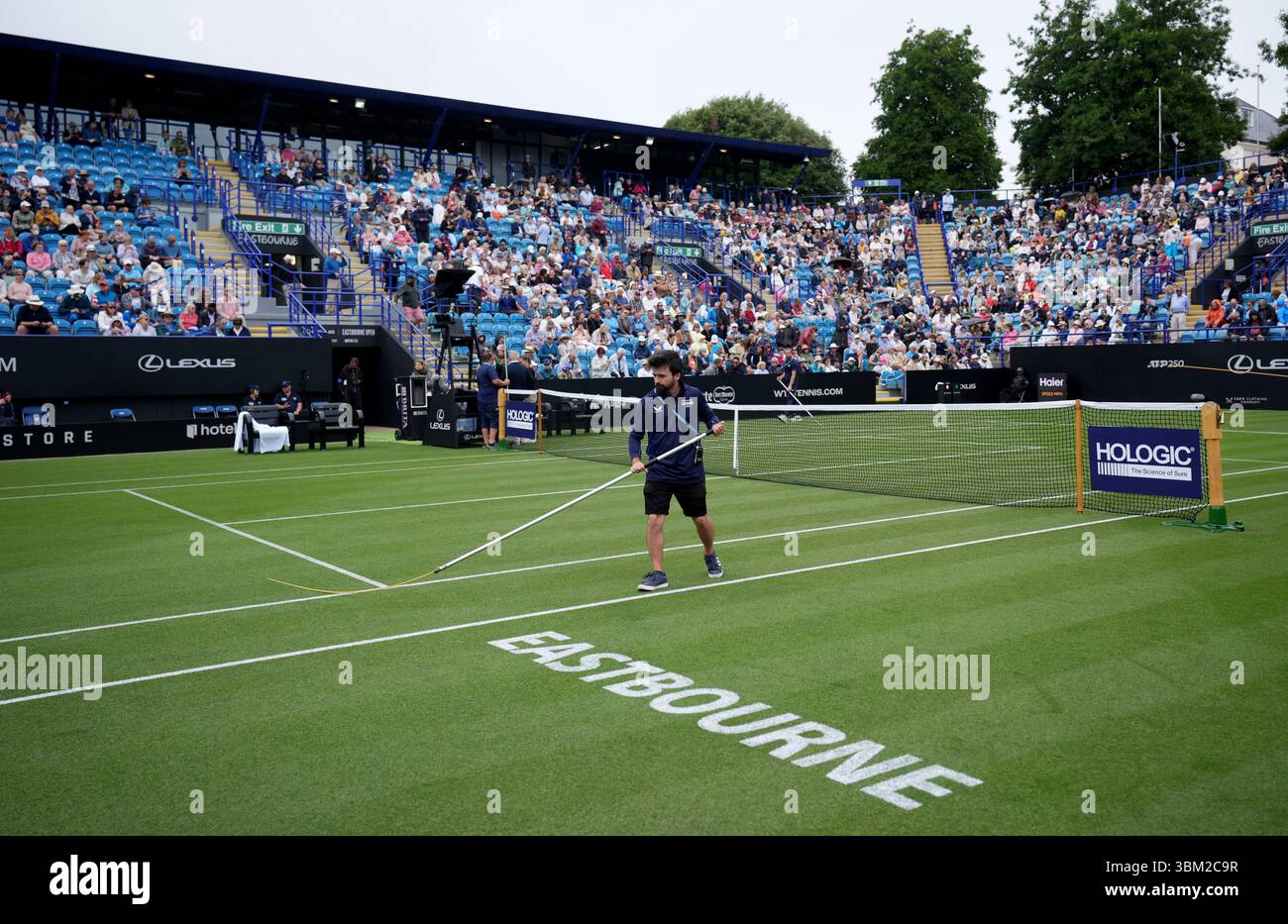 Ground staff attempt to dry the court during day two of the Lexus ...