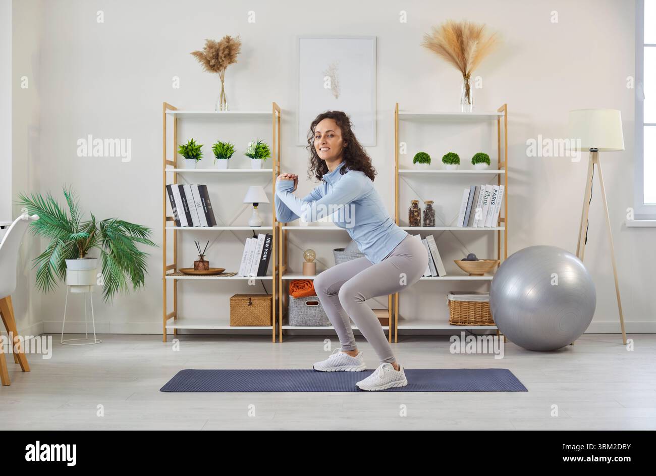 Active Woman Doing Squats In Home Gym Stock Photo - Alamy