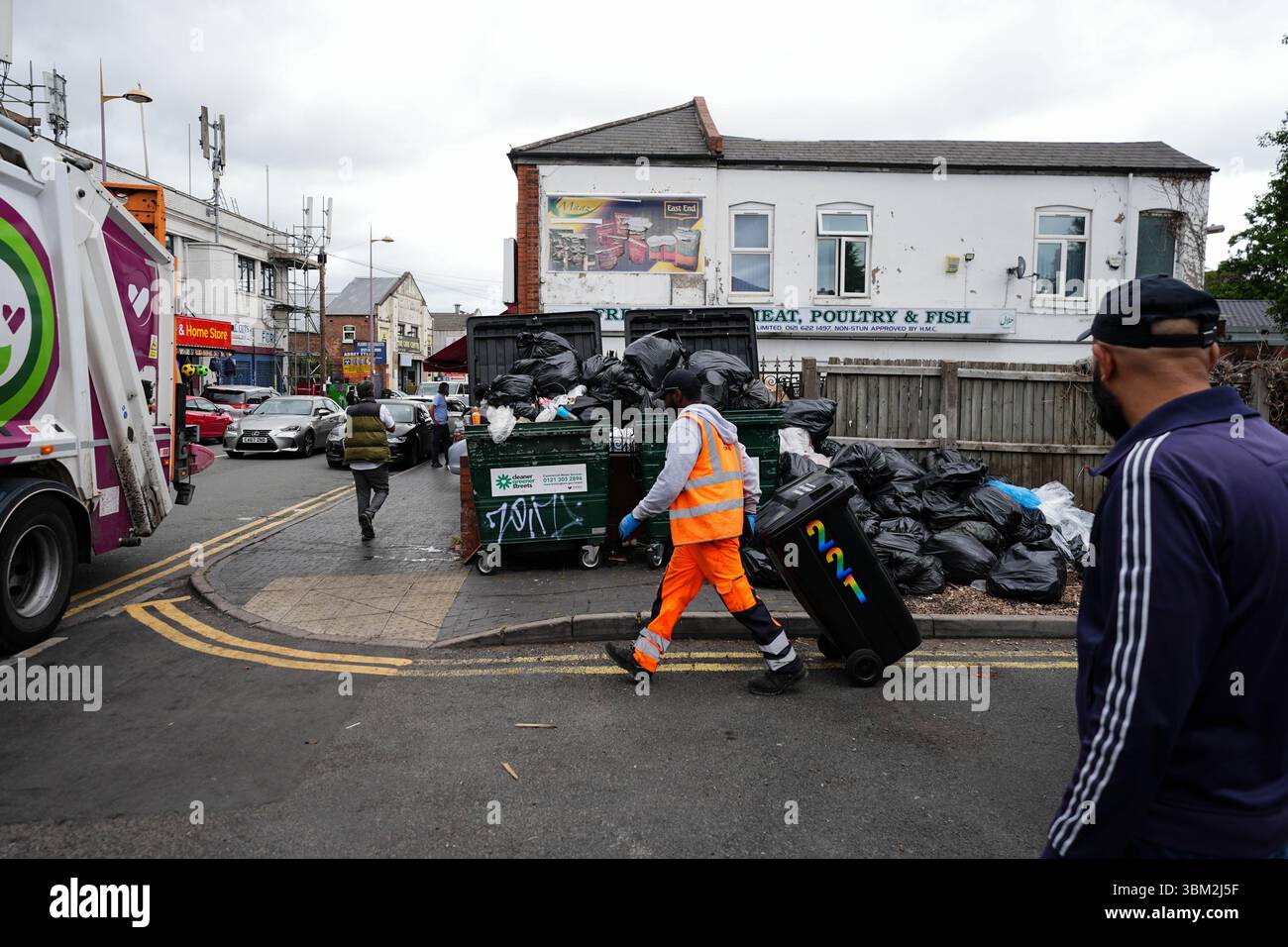 A refuse worker collects a bin by uncollected waste bags in the Aston ...