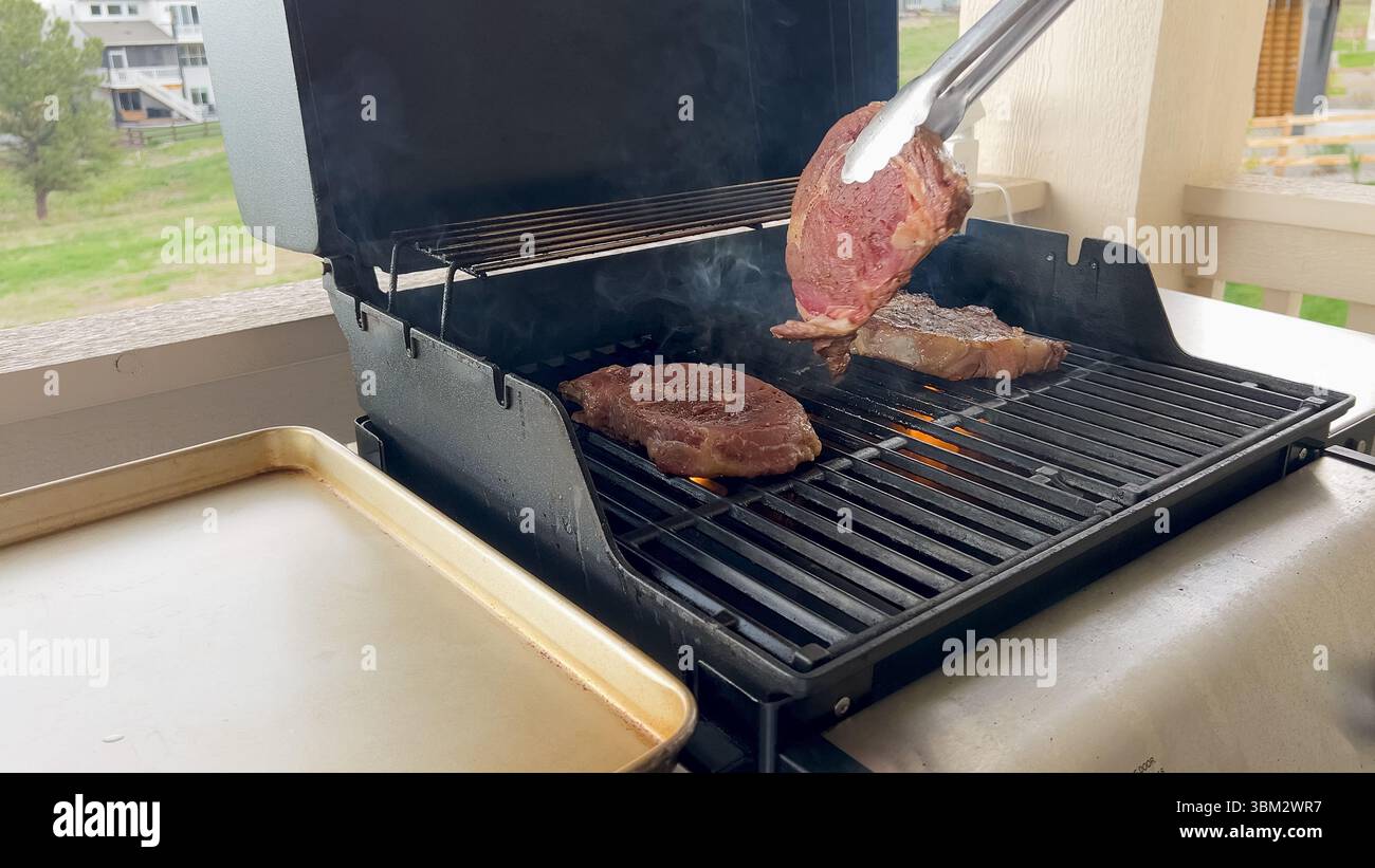 Grilling Steaks on Open Gas Grill with Tongs Stock Photo - Alamy
