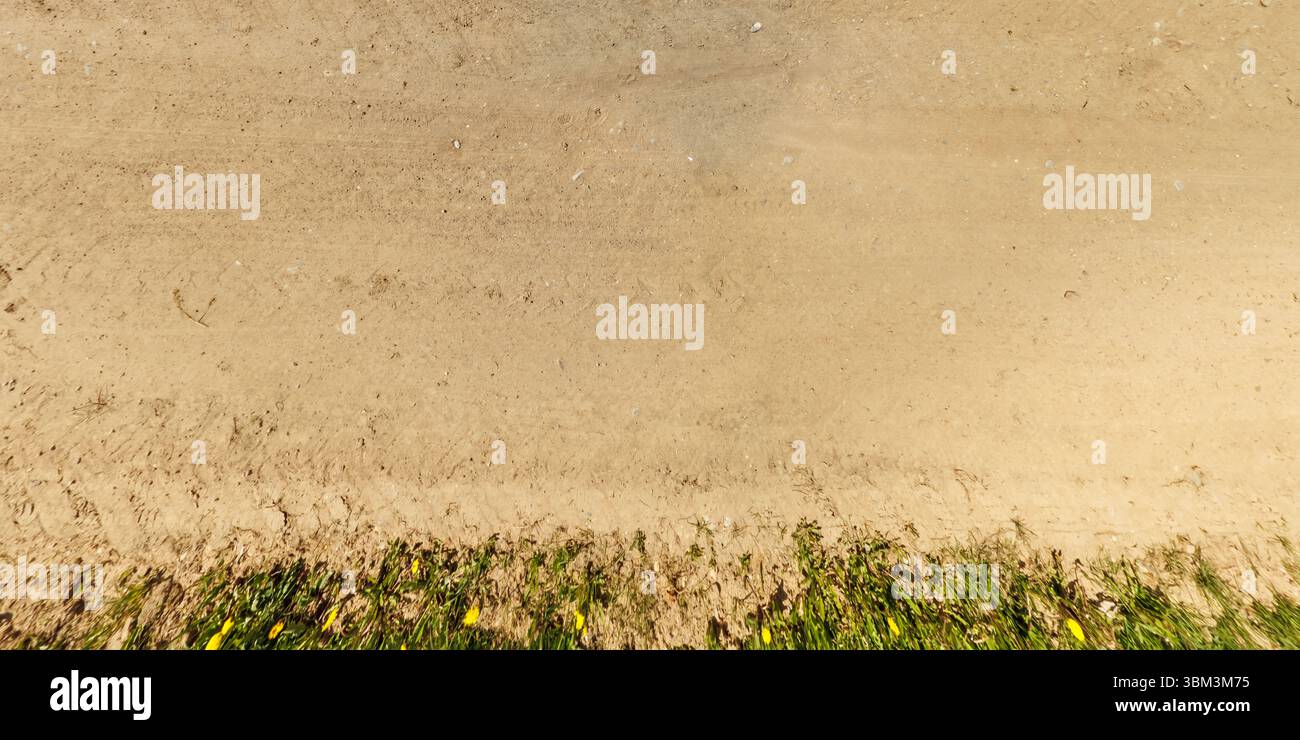 top view of gravel road surface and grass shoulder with tractor tire ...