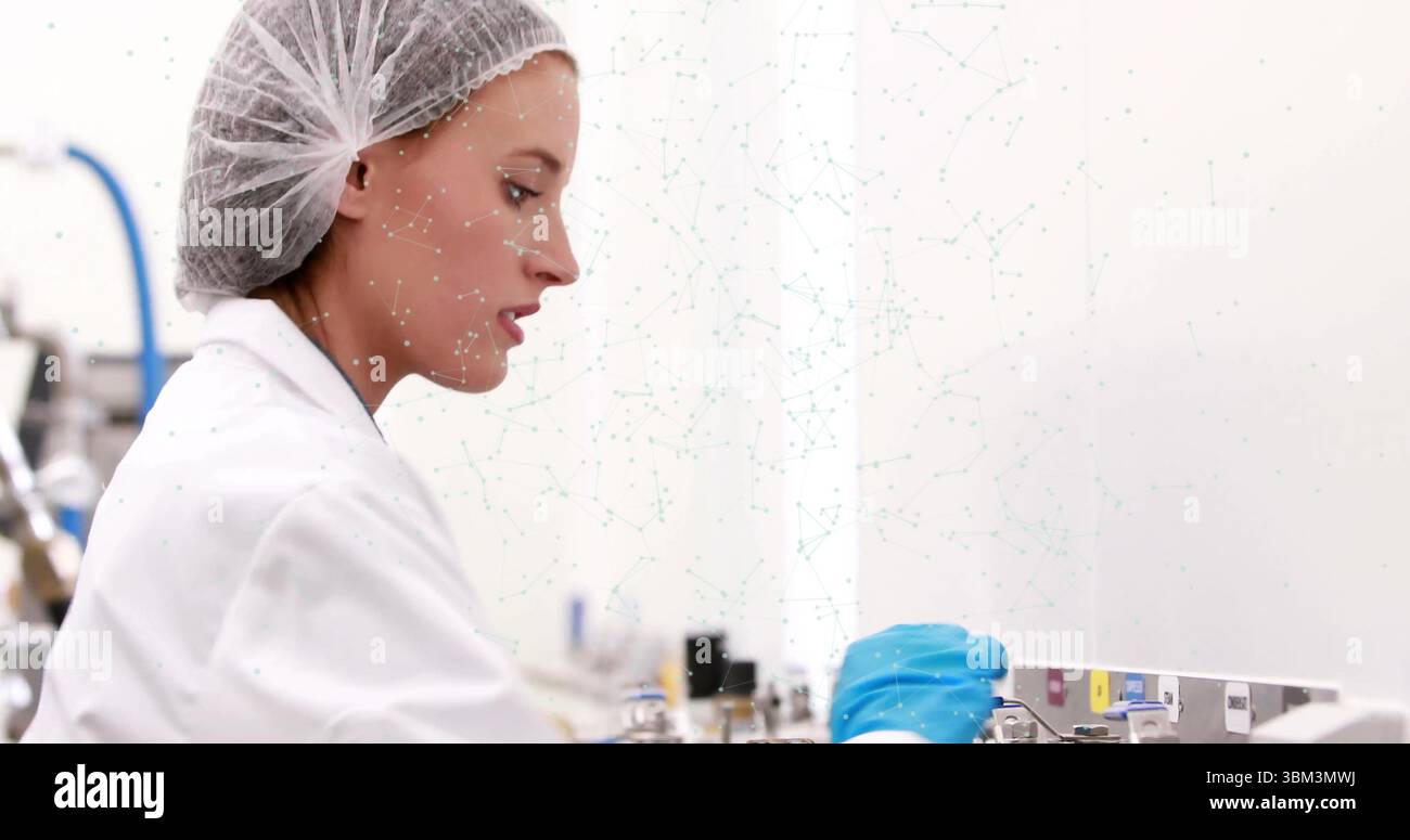 Operating technician wearing lab coat, hairnet, adjusting panel labels ...