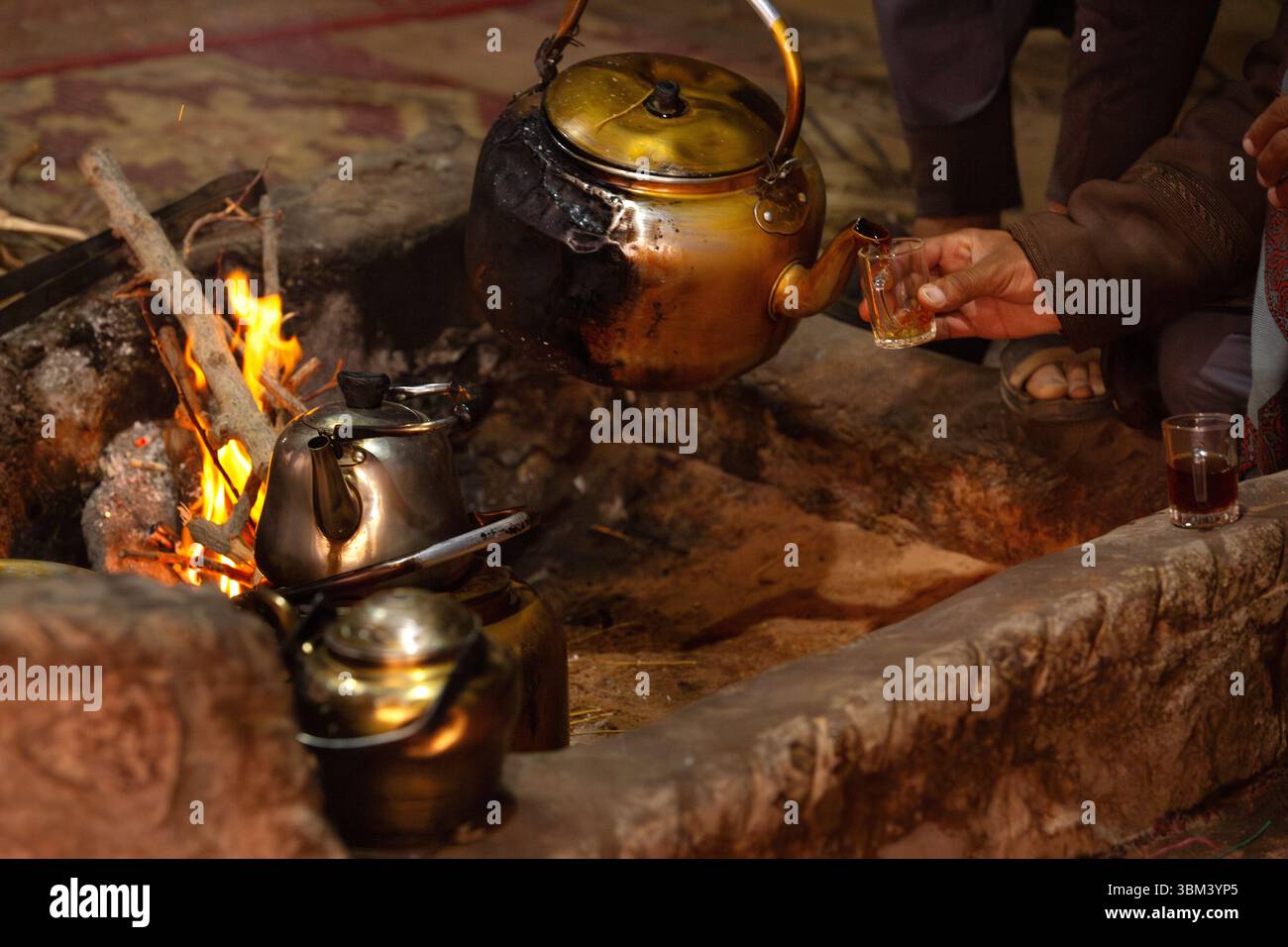 Arab Bedouin man hand, pouring tea from kettle into glass traditional ...