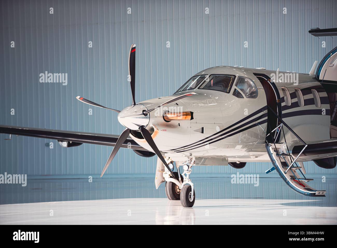 Side-front view of a turboprop aircraft parked inside a hangar with the ...