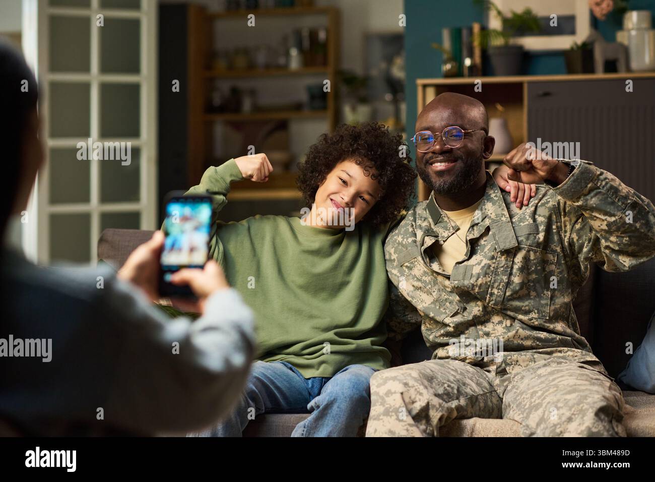Black middle aged man in military uniform sitting on couch with smiling ...