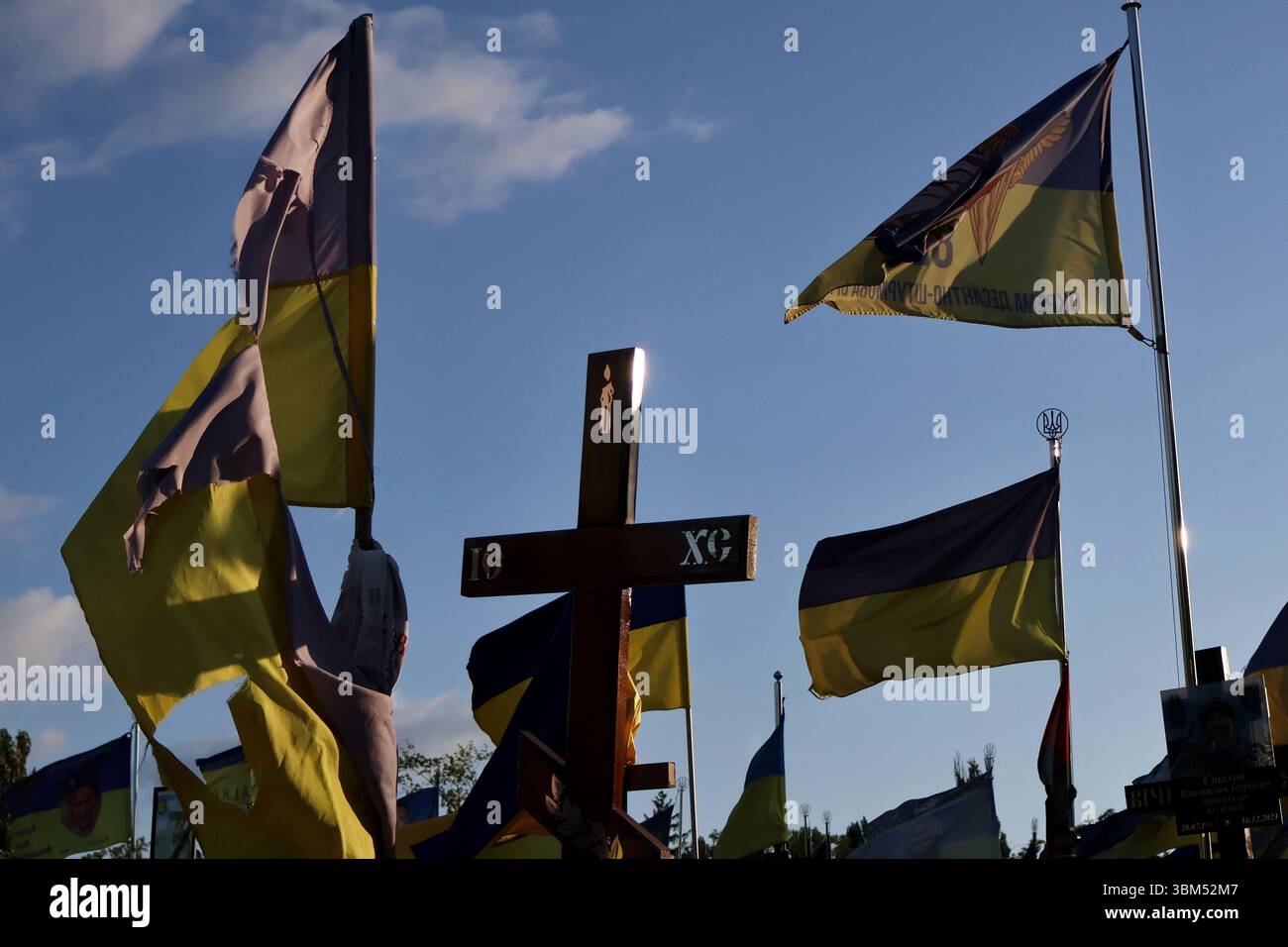 Kyiv, Ukraine. 24th June, 2025. A cross in the center and flags against ...