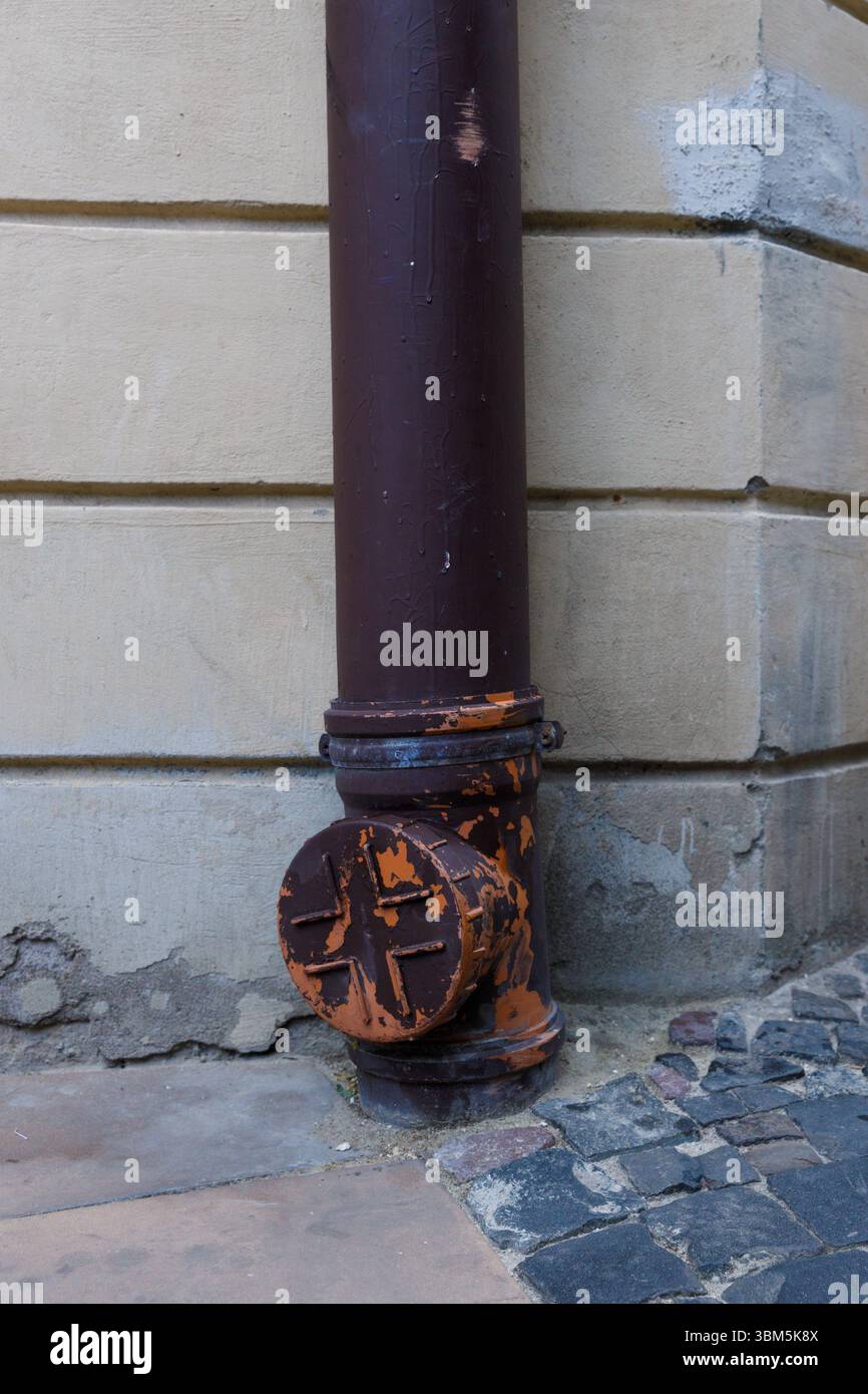 This image features a brown drain pipe attached to a wall, showcasing a ...