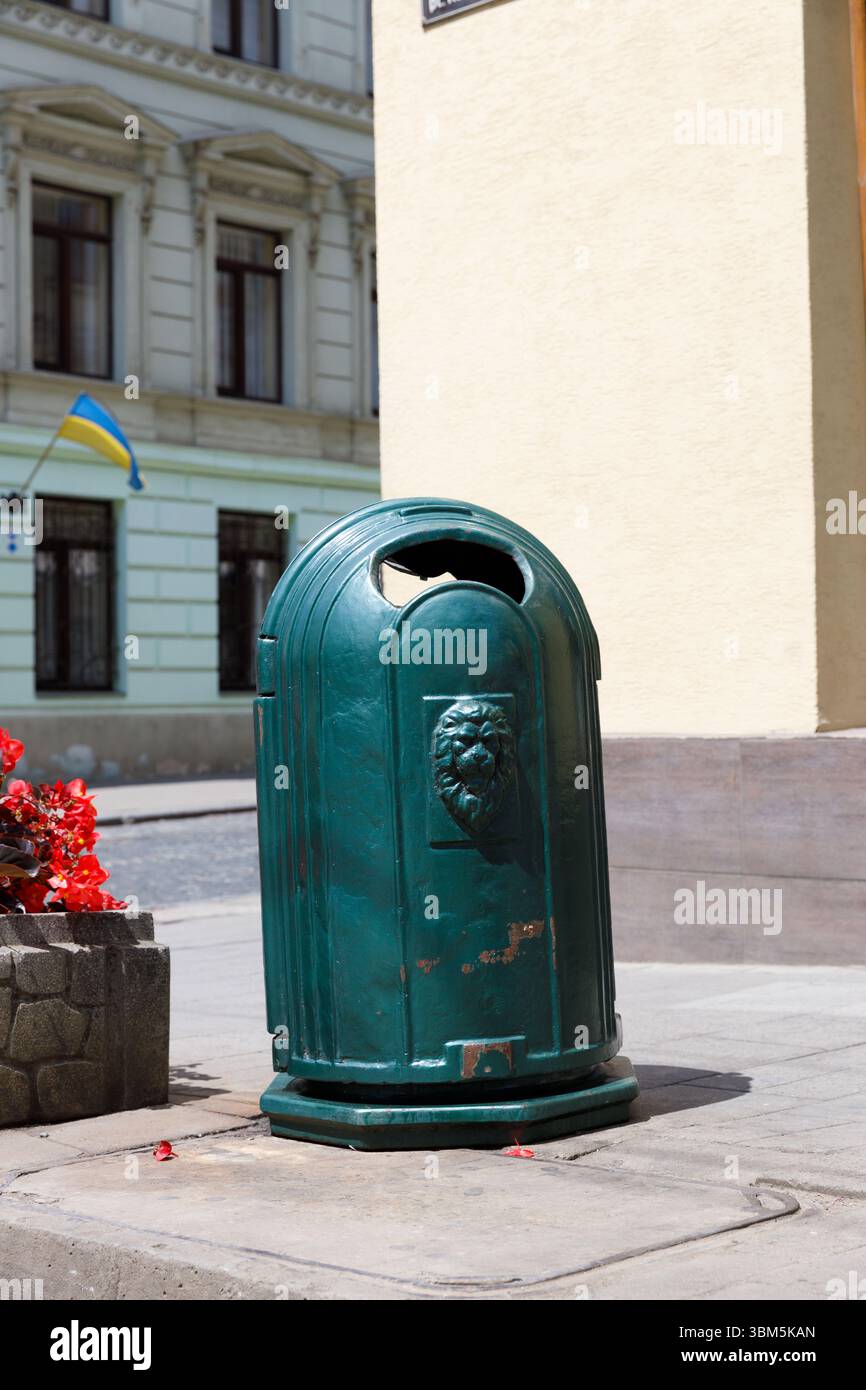 The image showcases a green trash bin with a lion motif placed beside a ...