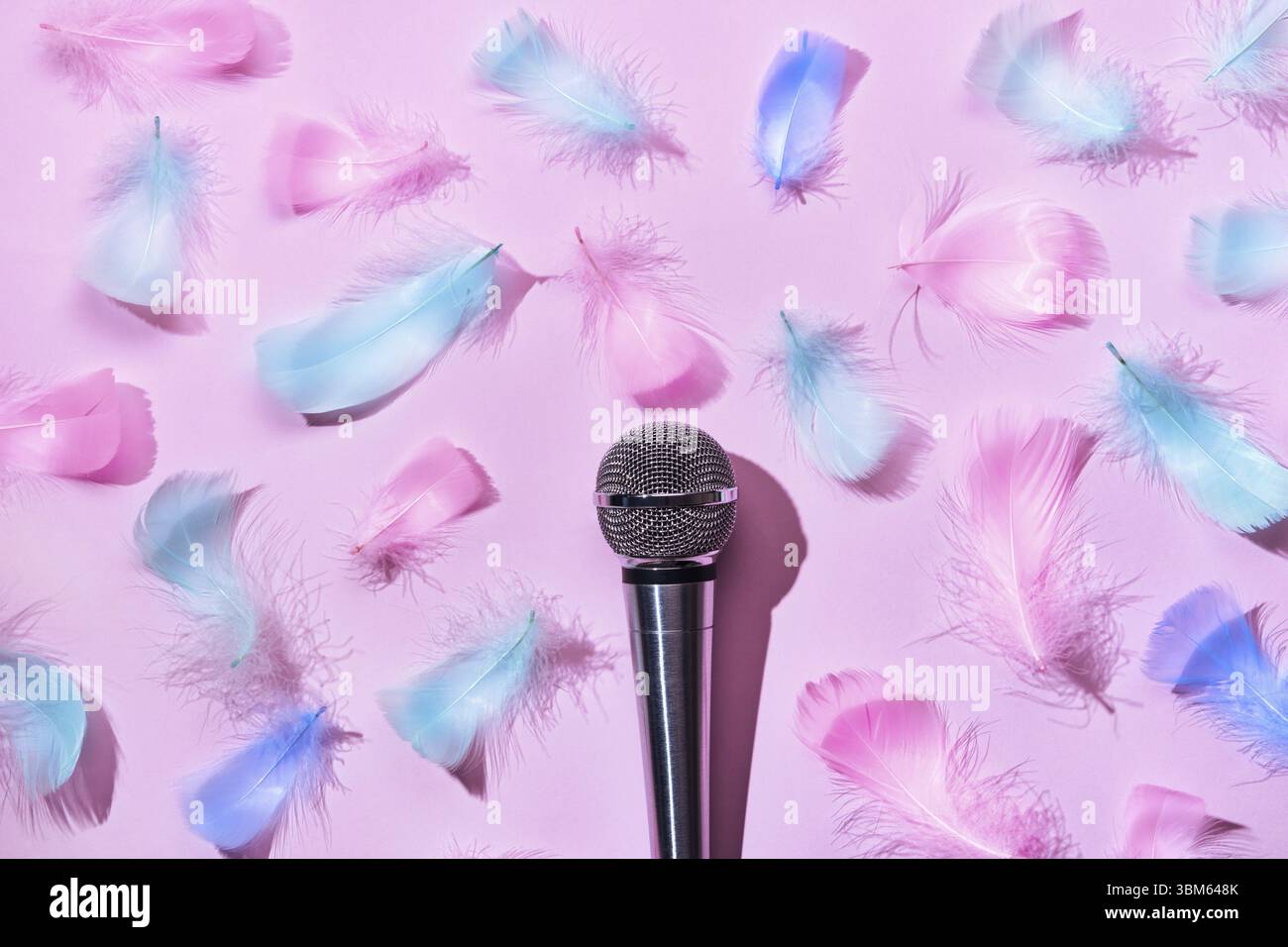 Microphone and soft feathers on pink background. ASMR recording stress ...