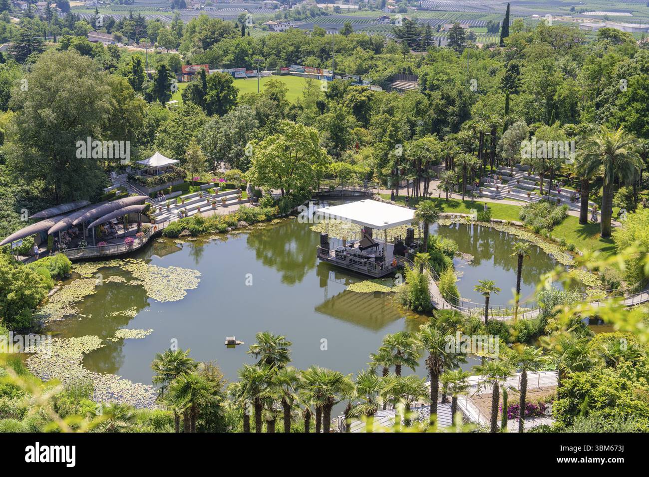 A pond with a pavilion in the middle of a green park, surrounded by ...