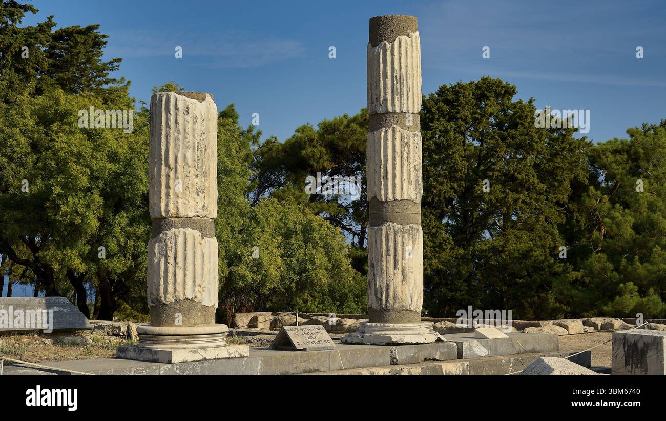Two massive stone columns standing in a green, tree-filled environment ...