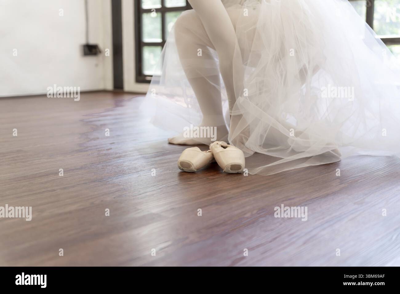 Ballerina in ballet shoes. Asian girl tying ribbons of toe shoes ...