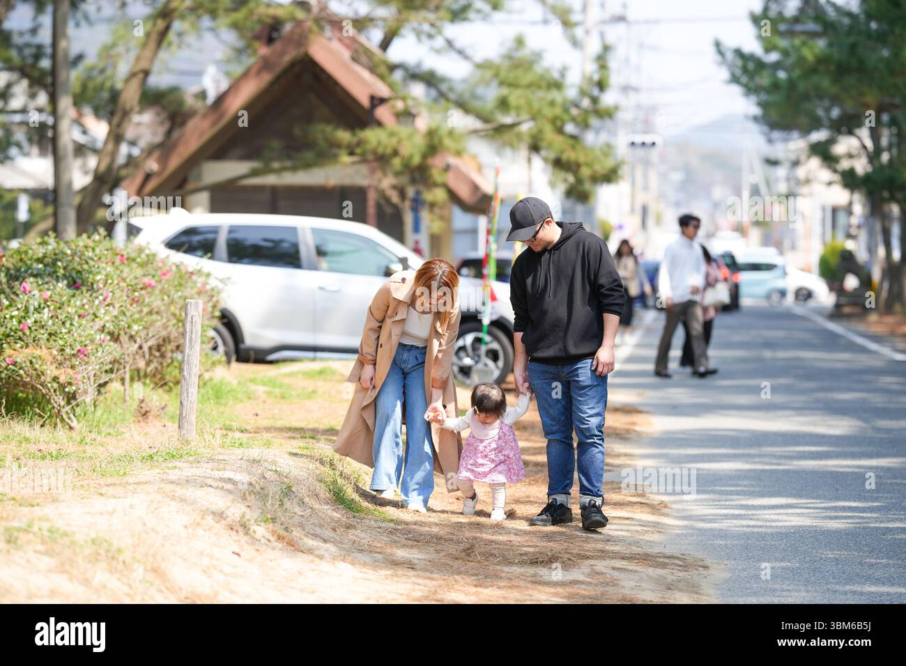 Japanese family walking through town in early spring: a 30-something father and mother with ...