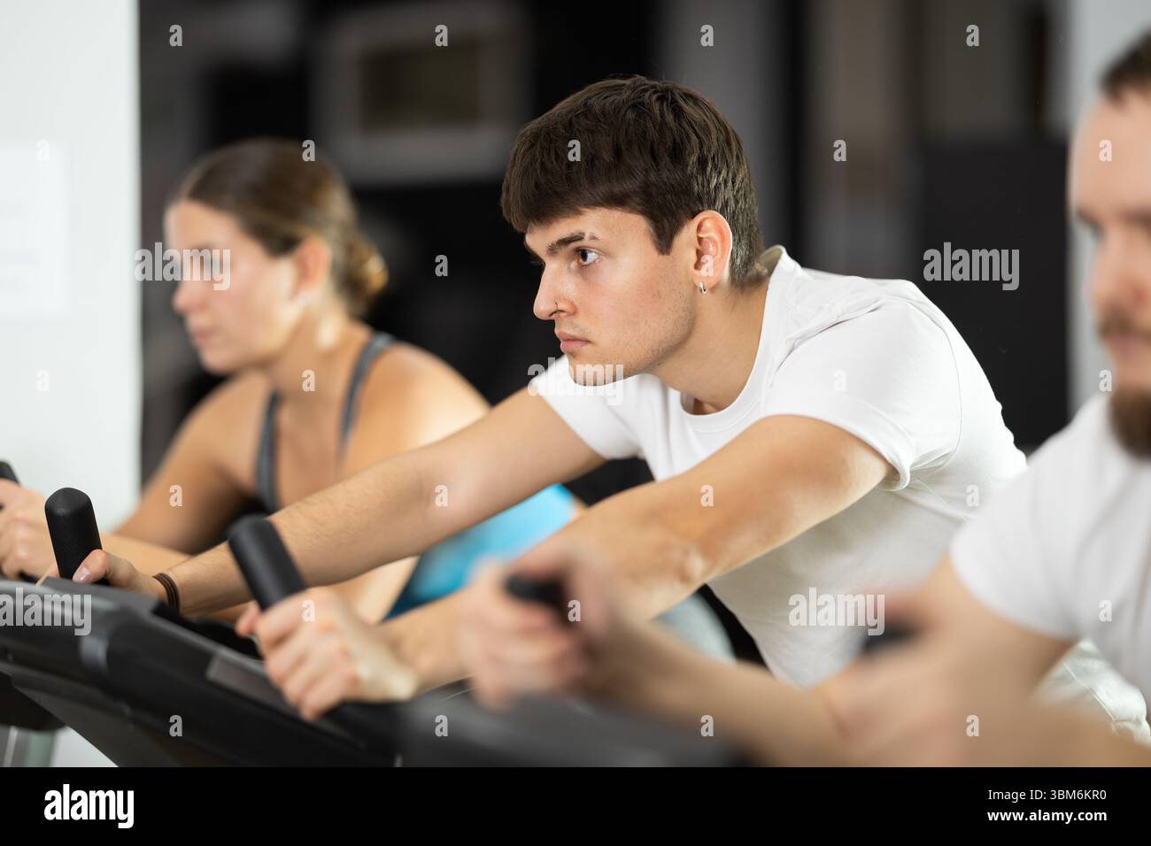 Focused guy works out with stationary bicycle during class at fitness ...
