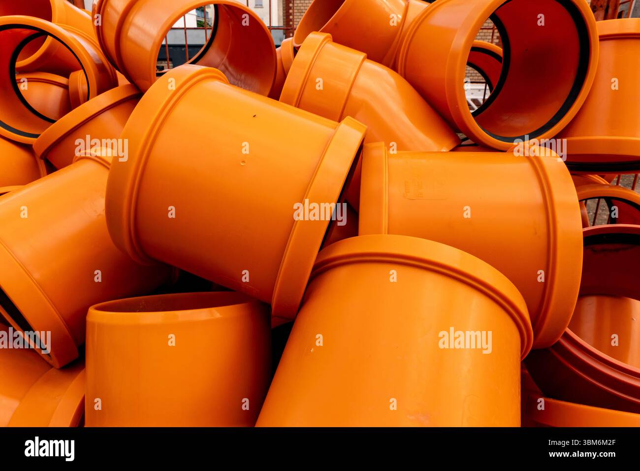 Orange pvc pipes and connectors are stacked together, ready for use in a plumbing or sewerage ...