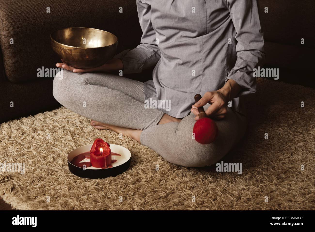 Faceless woman meditates at home on carpet and plays on copper singing ...