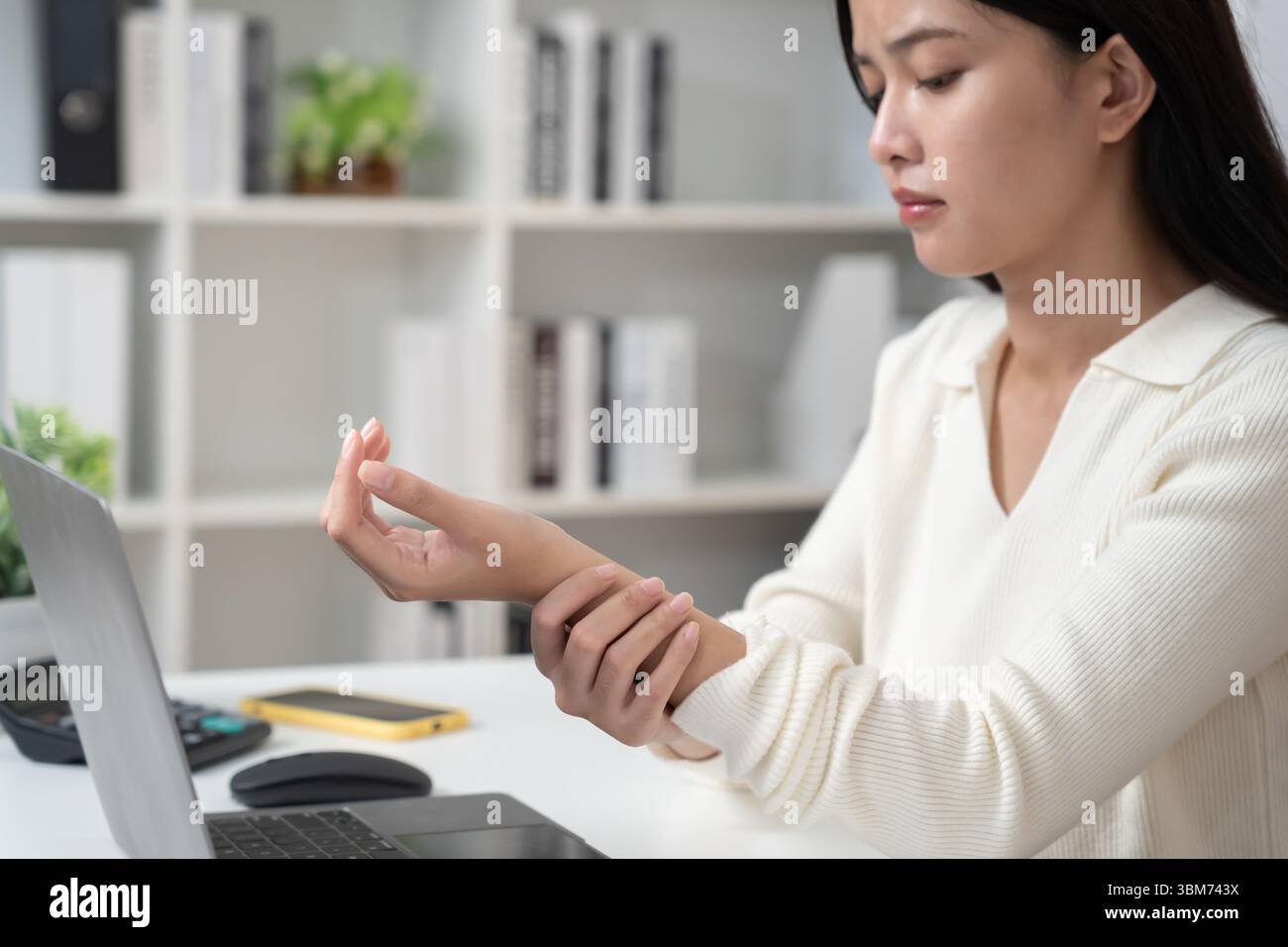 young woman working in office with a carpal tunnel syndrome or wrist ...