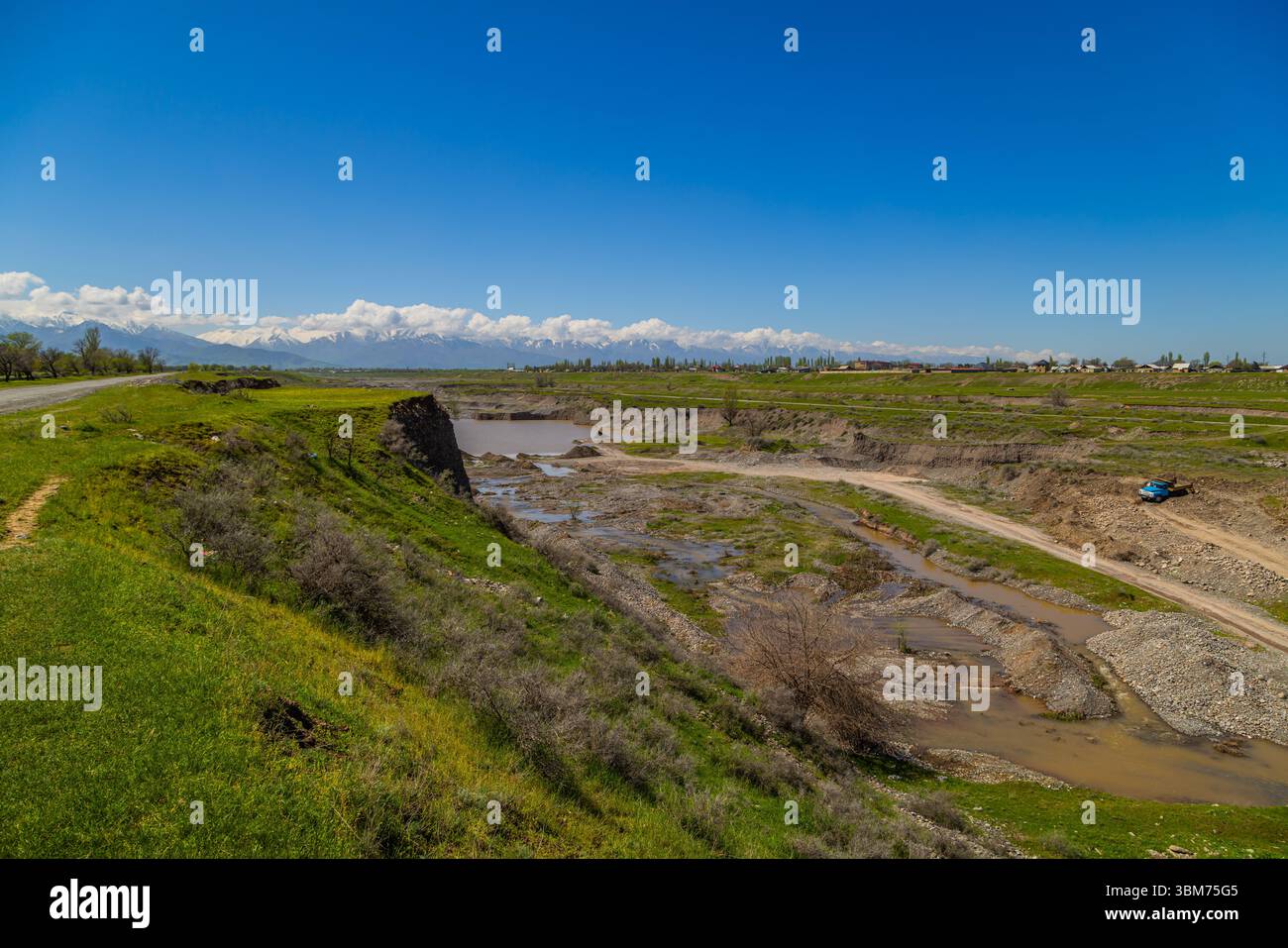 Truck parked by meandering river in rock quarry in Kyrgyzstan. Shallow ...