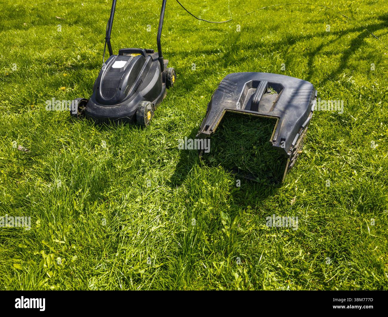 Lawn mower and grass catcher in serene garden setting Stock Photo - Alamy