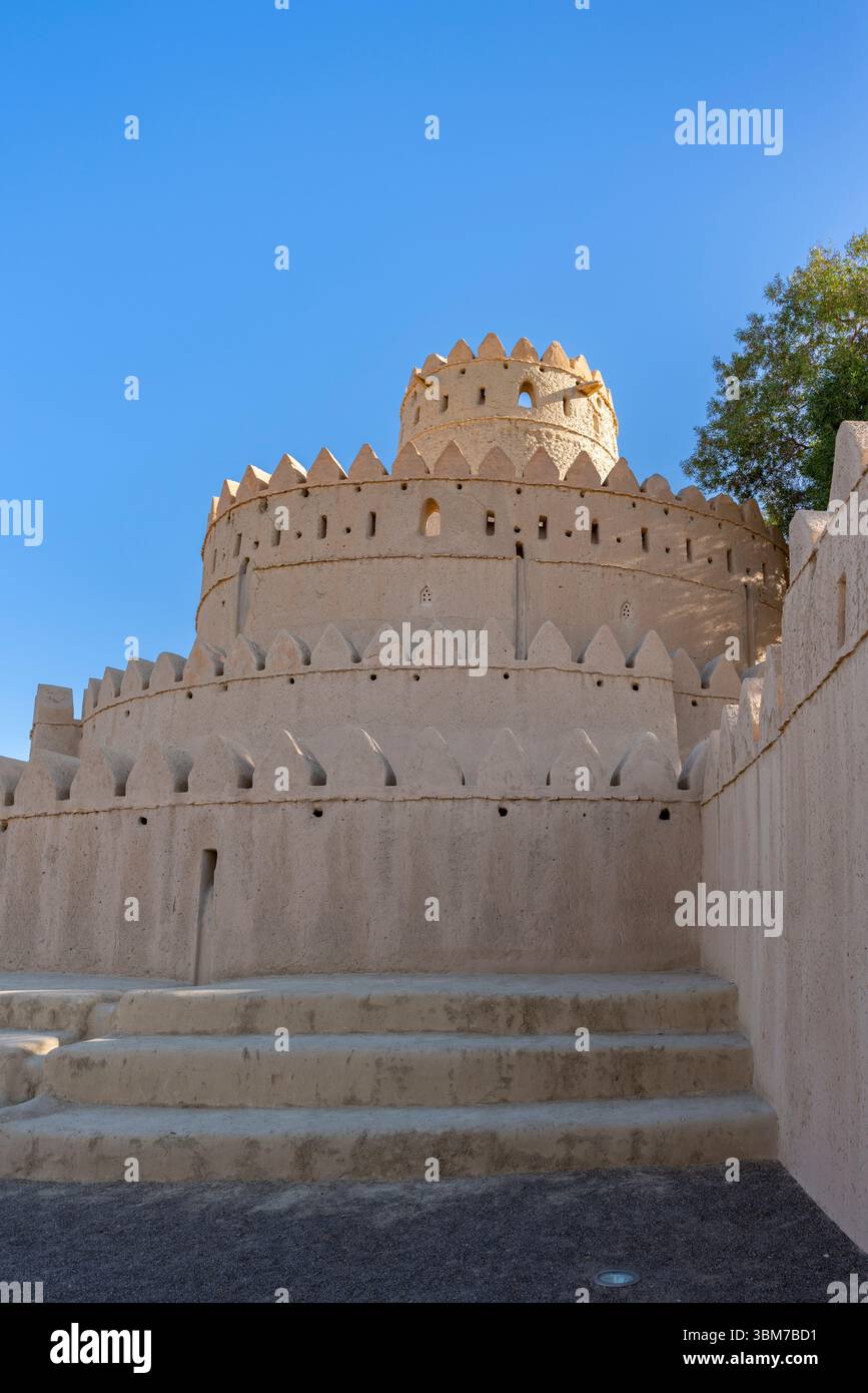 Circular mud brick tower with stepped crenellations rises above ...