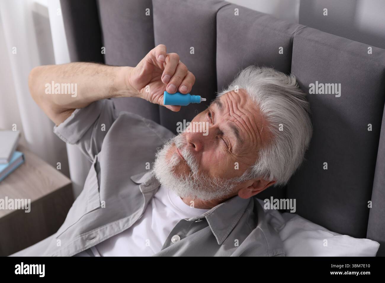 Senior man applying eye drops on bed at home, above view Stock Photo ...