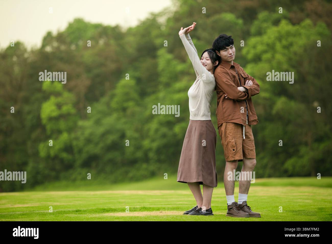 A young couple standing back-to-back Stock Photo - Alamy