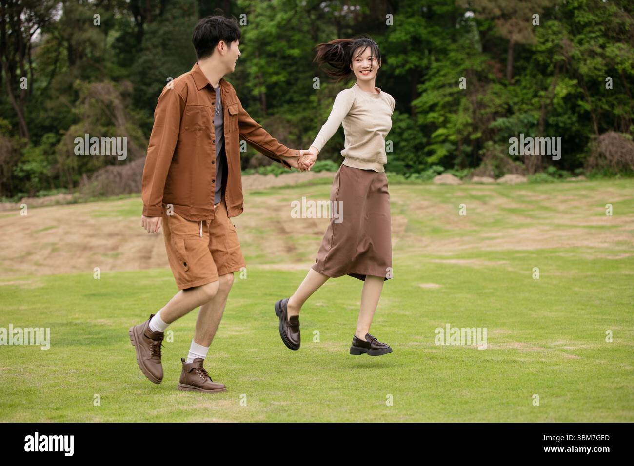 A young couple happily running and chasing each other on the lawn Stock ...