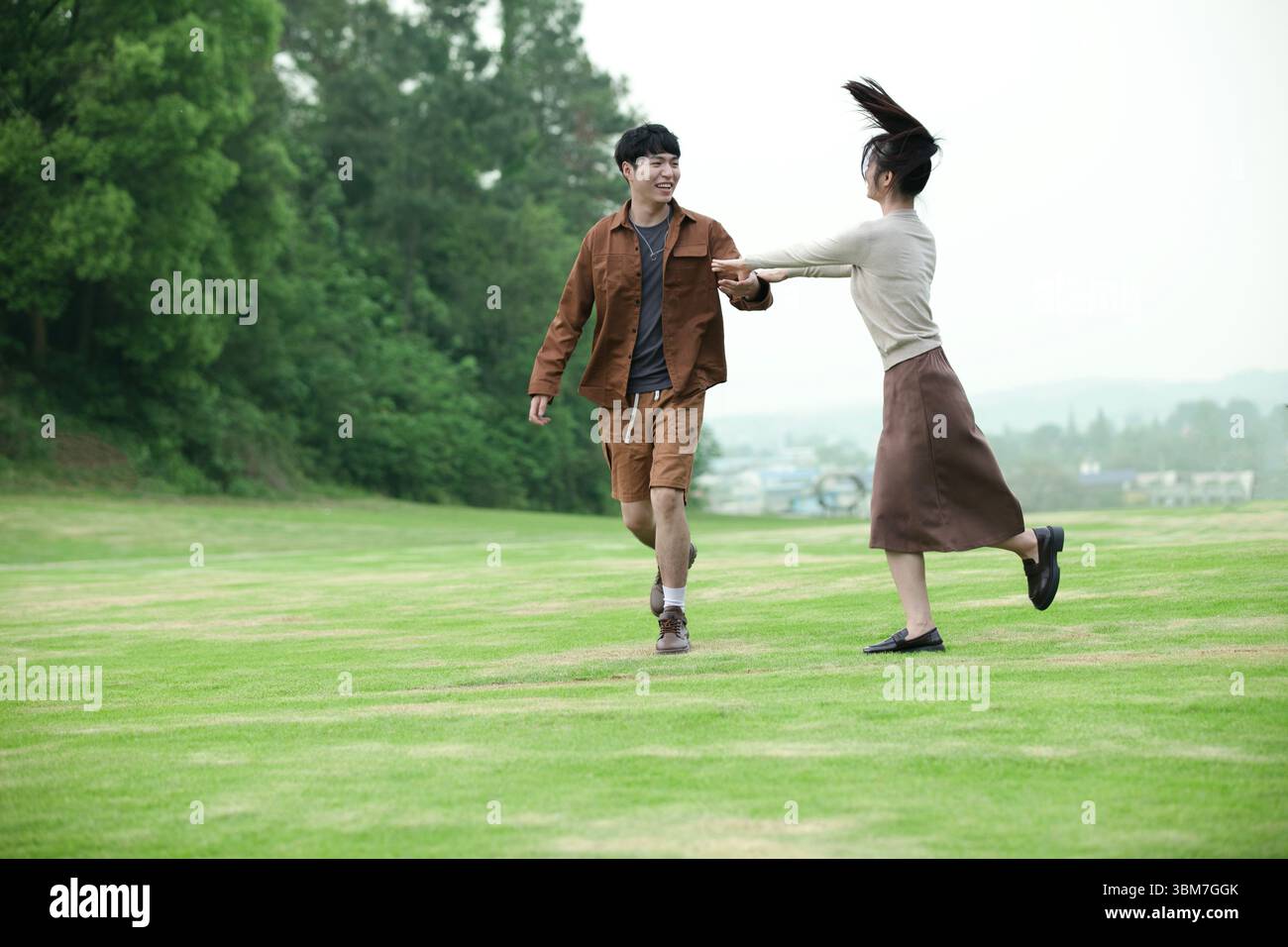 A young couple happily running and chasing each other on the lawn Stock ...