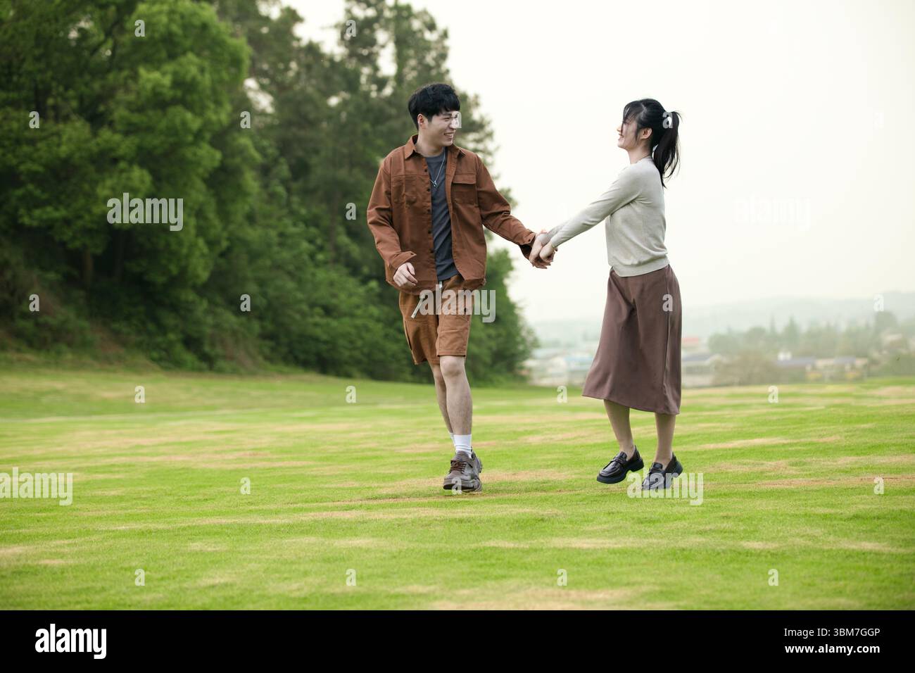 A young couple happily running and chasing each other on the lawn Stock ...