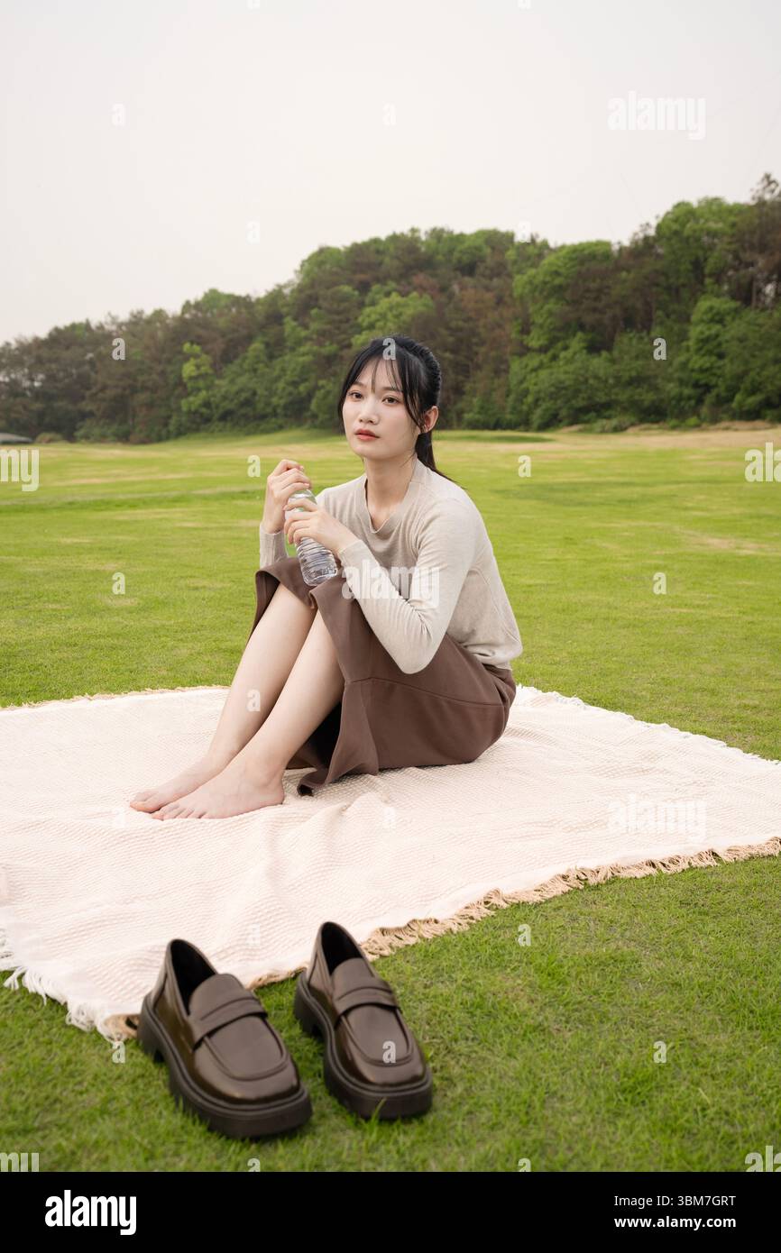 A young Chinese woman resting on an outdoor mat Stock Photo - Alamy