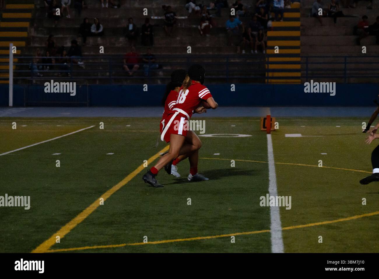 Title: Girls in red uniforms playing flag football on vibrant field ...