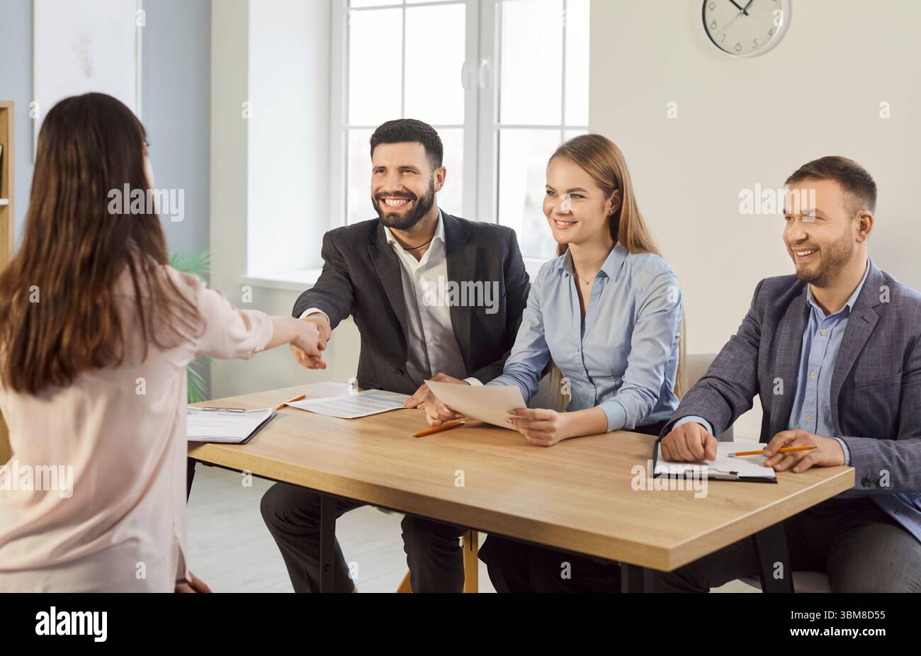 Smiling HR managers sitting at desk and shaking hands with female ...