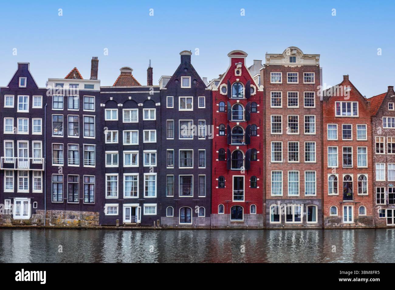 Colorful Damrak canal houses in Amsterdam, classic Dutch facades, picturesque waterfront view ...