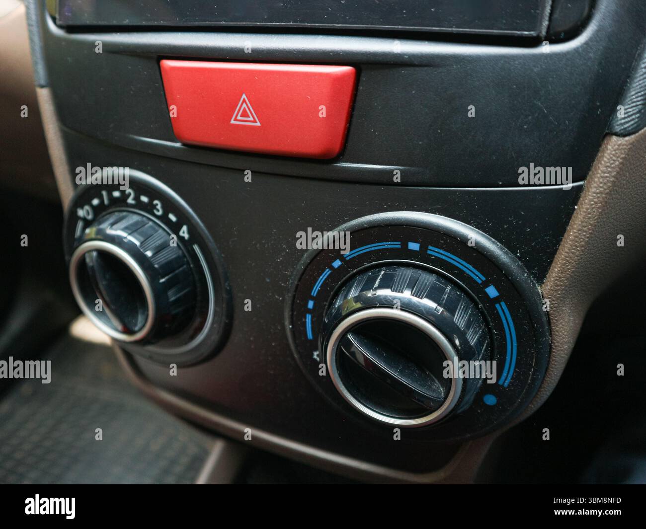 A car dashboard with air conditioning controls, including a red hazard ...
