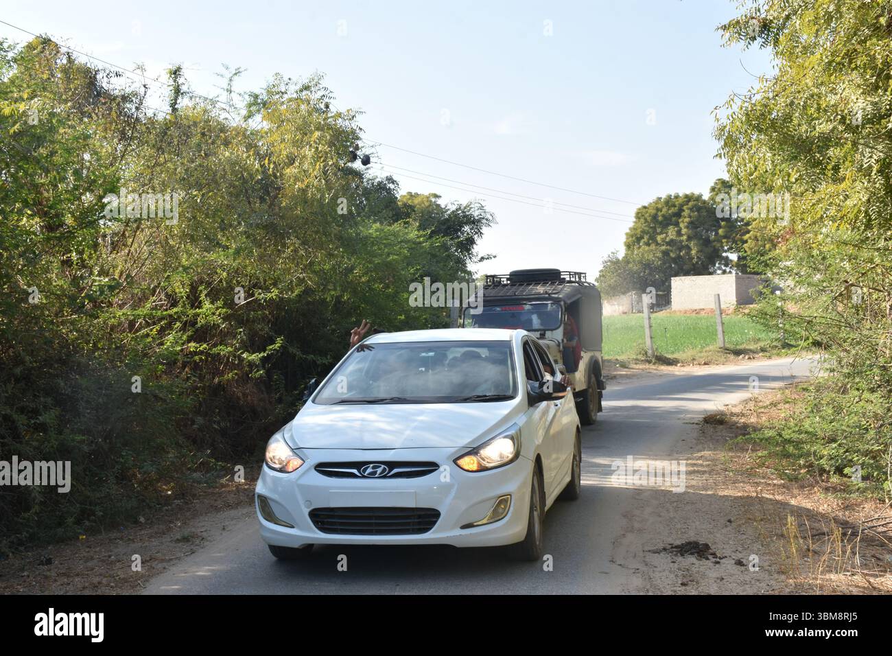 White Hyundai car driving on a rural road with greenery and trailing ...