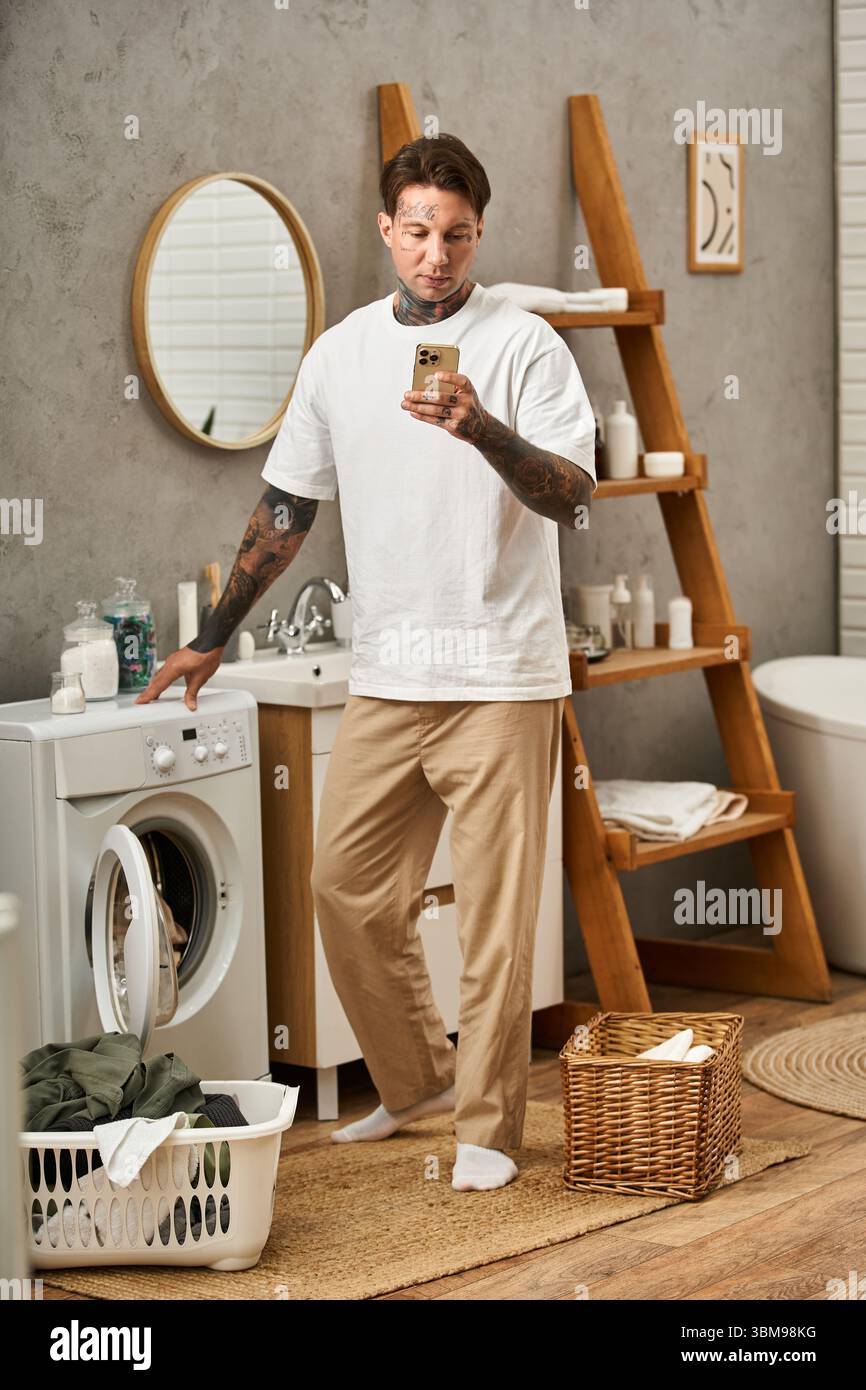 Young man with tattoos relaxes in his home, checking his phone while ...