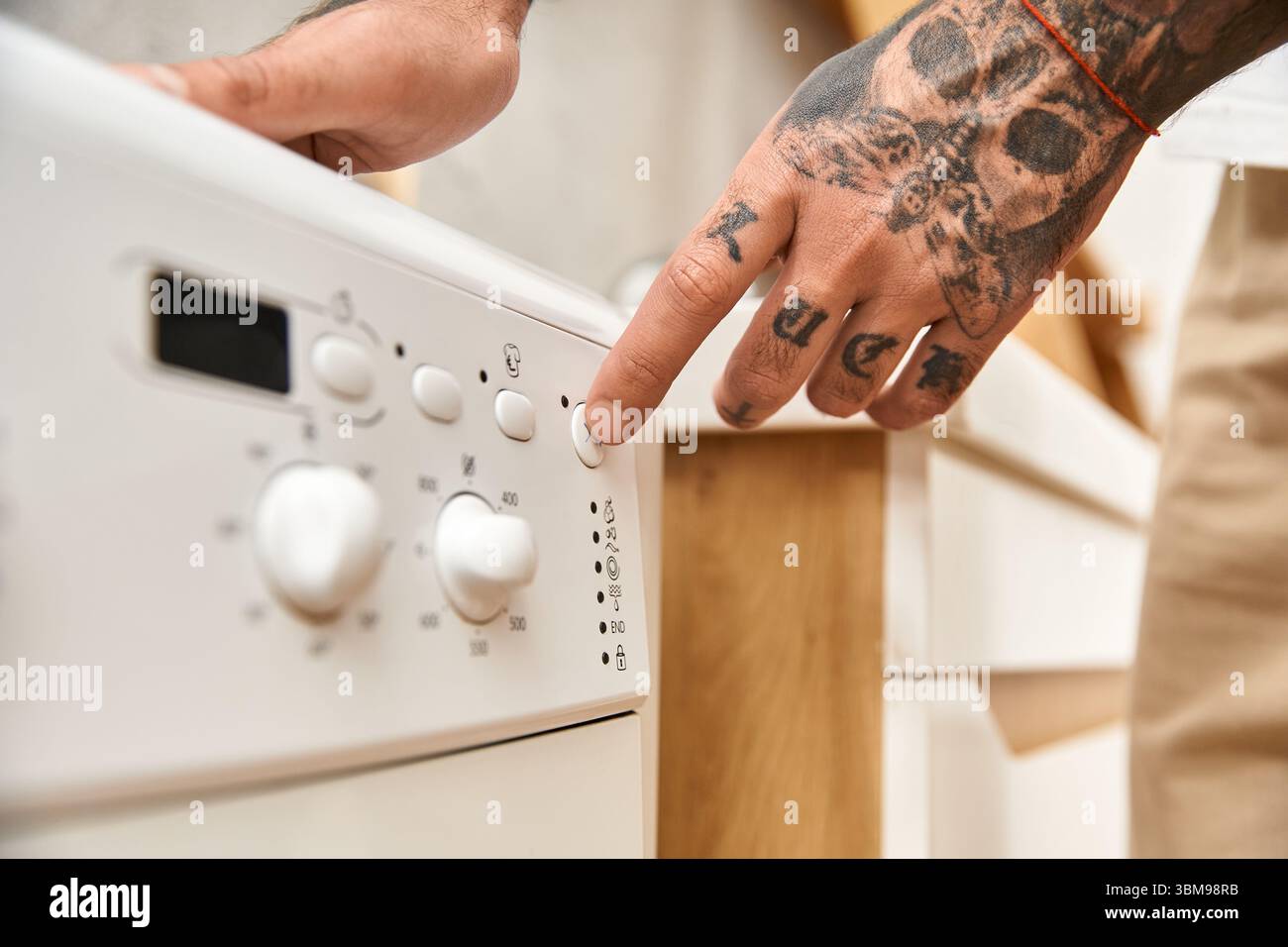 A young man with tattoos relaxes at home, adjusting the laundry ...