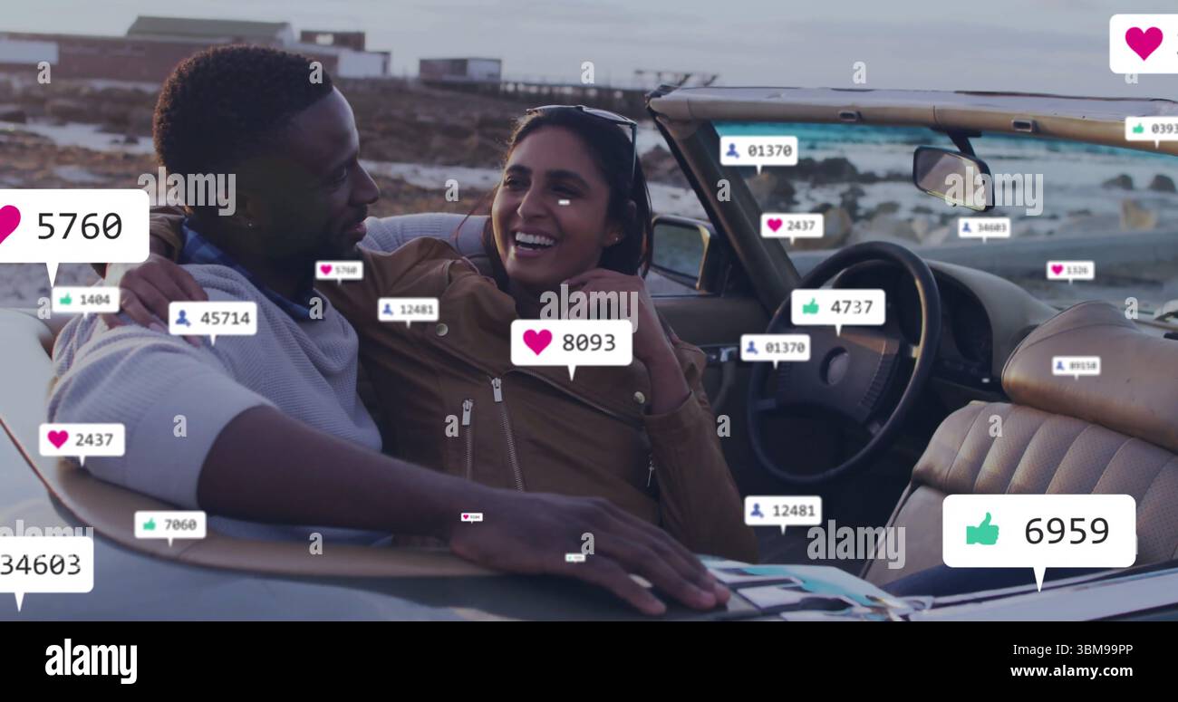 Laughing couple leaning together in convertible car at rocky shoreline, with map and digital ...