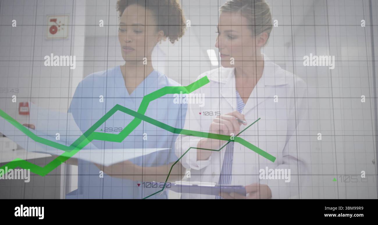 Medical staff in uniform reviewing data in hospital hall holding charts ...