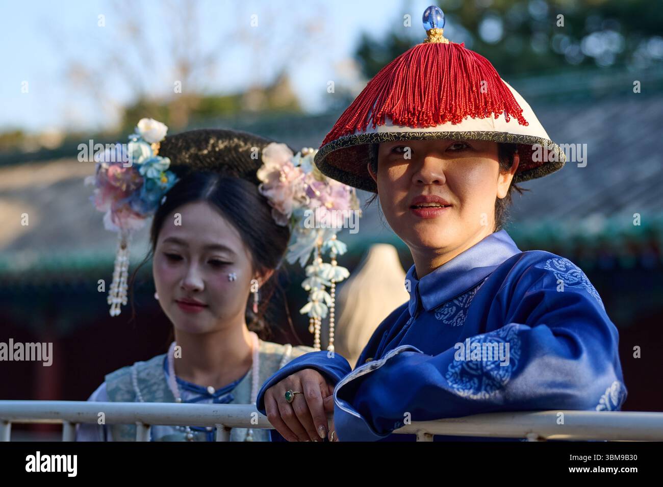 Two women in traditional Chinese outfits walking across ornate stone ...