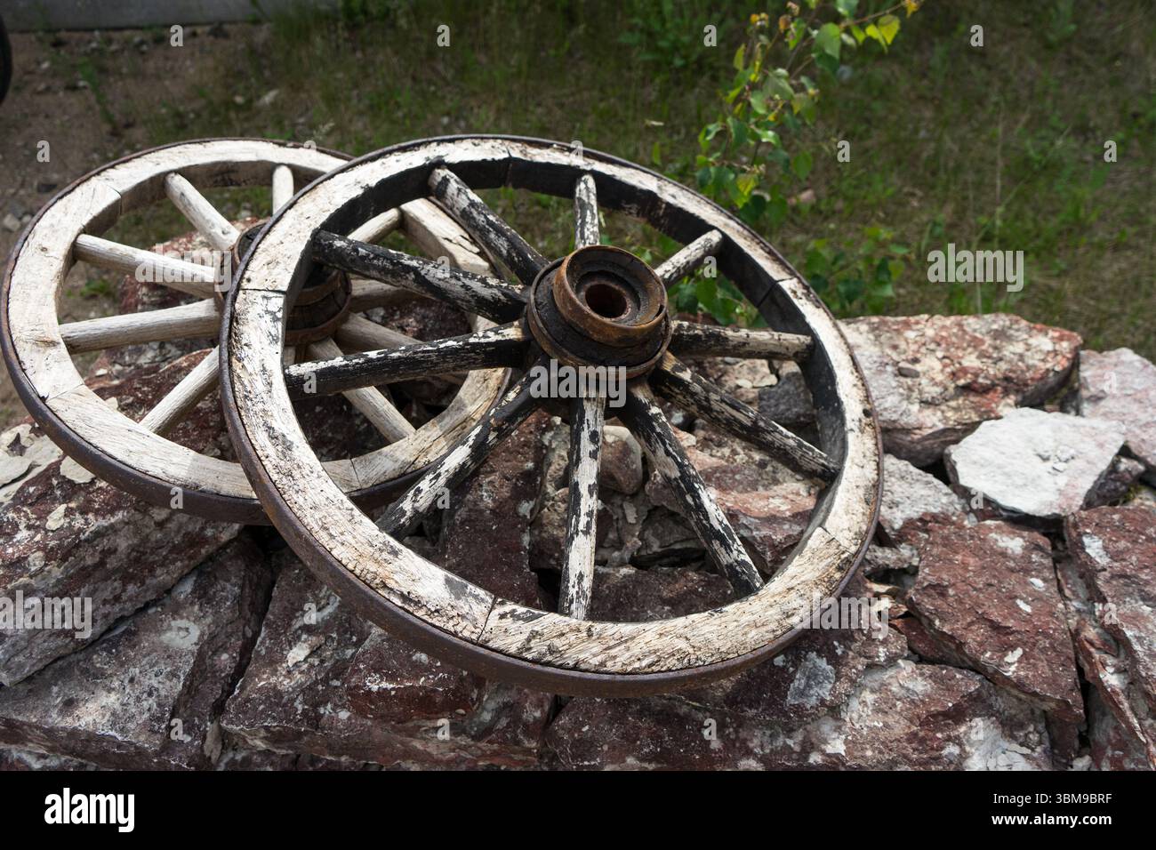 old, aged wagon wheels resting on rough stone wall Stock Photo - Alamy