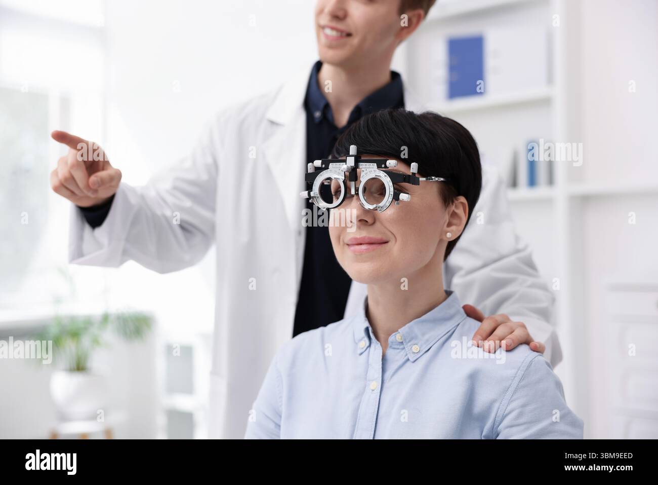 Ophthalmologist examining patient's vision with trial frame in clinic ...